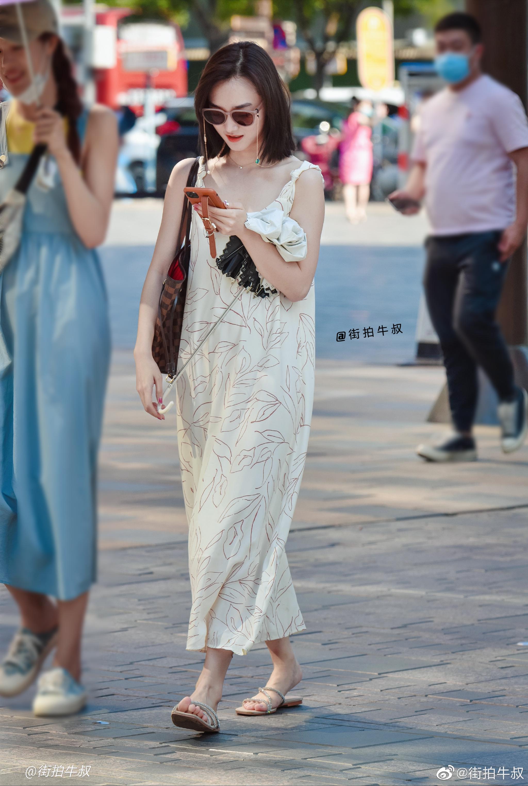 美女穿着可爱的印花吊带裙出街